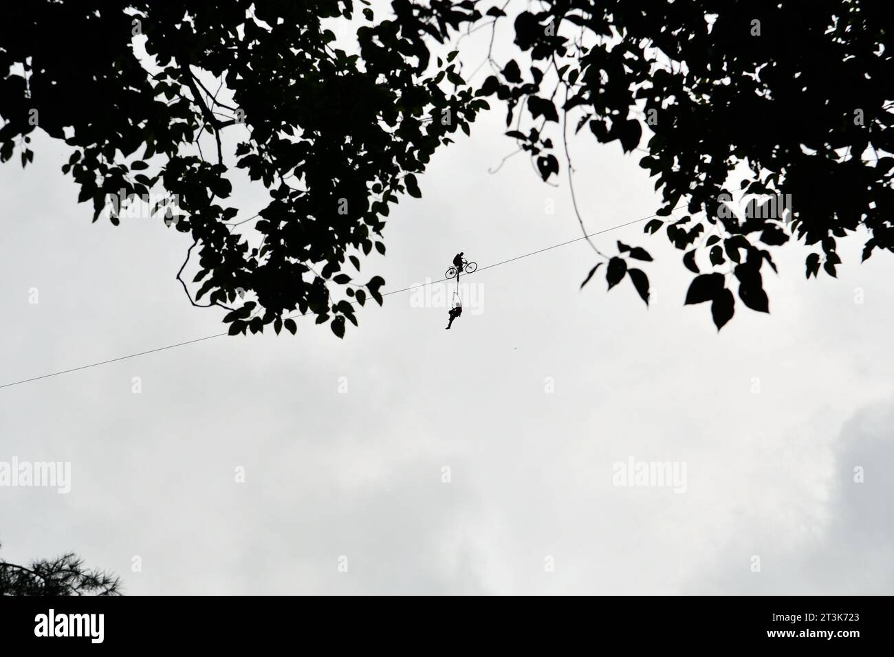 Silhouette photo of two people, high-altitude tightrope cycling ...