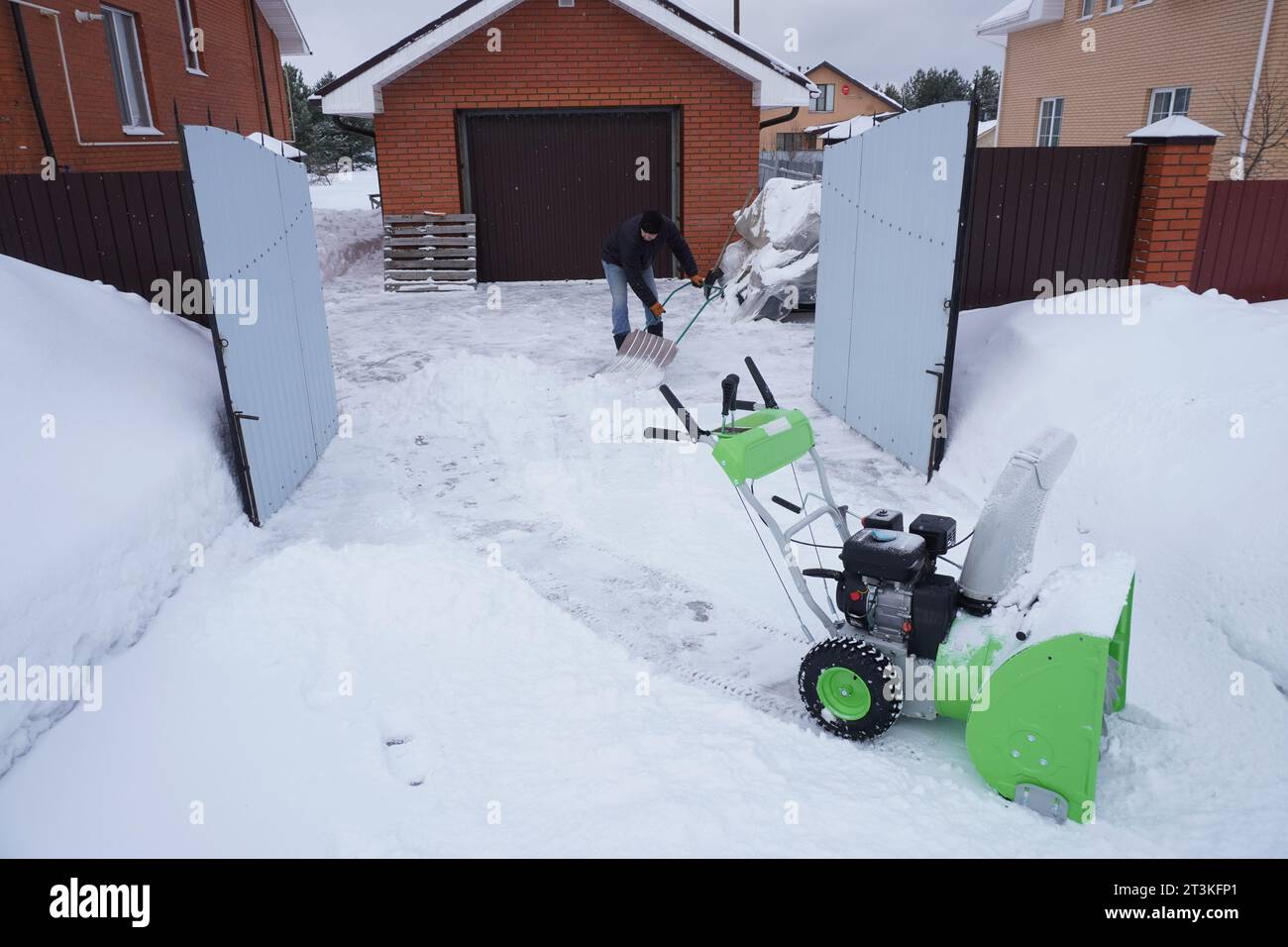 A man cleans snow in the winter in the courtyard of the house, man ...