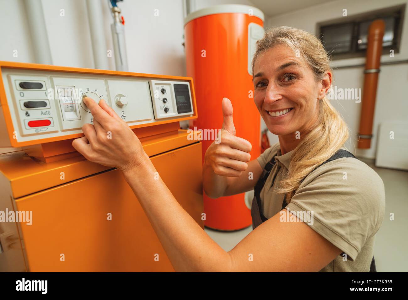 Happy female heating engineer shows thumb up in a boiler room with a ...