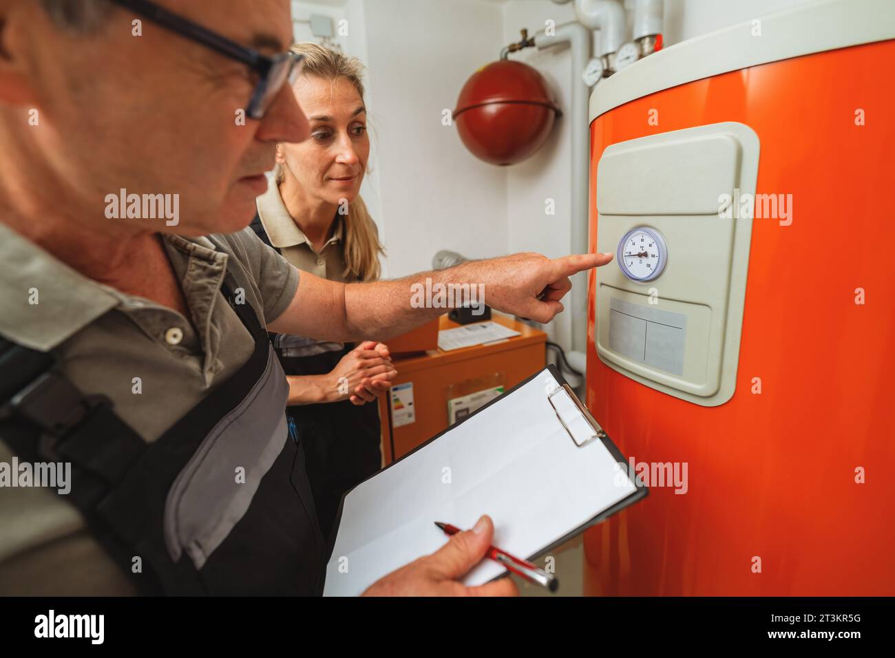 Team of heating engineers checks a old gas heating system thermostat ...