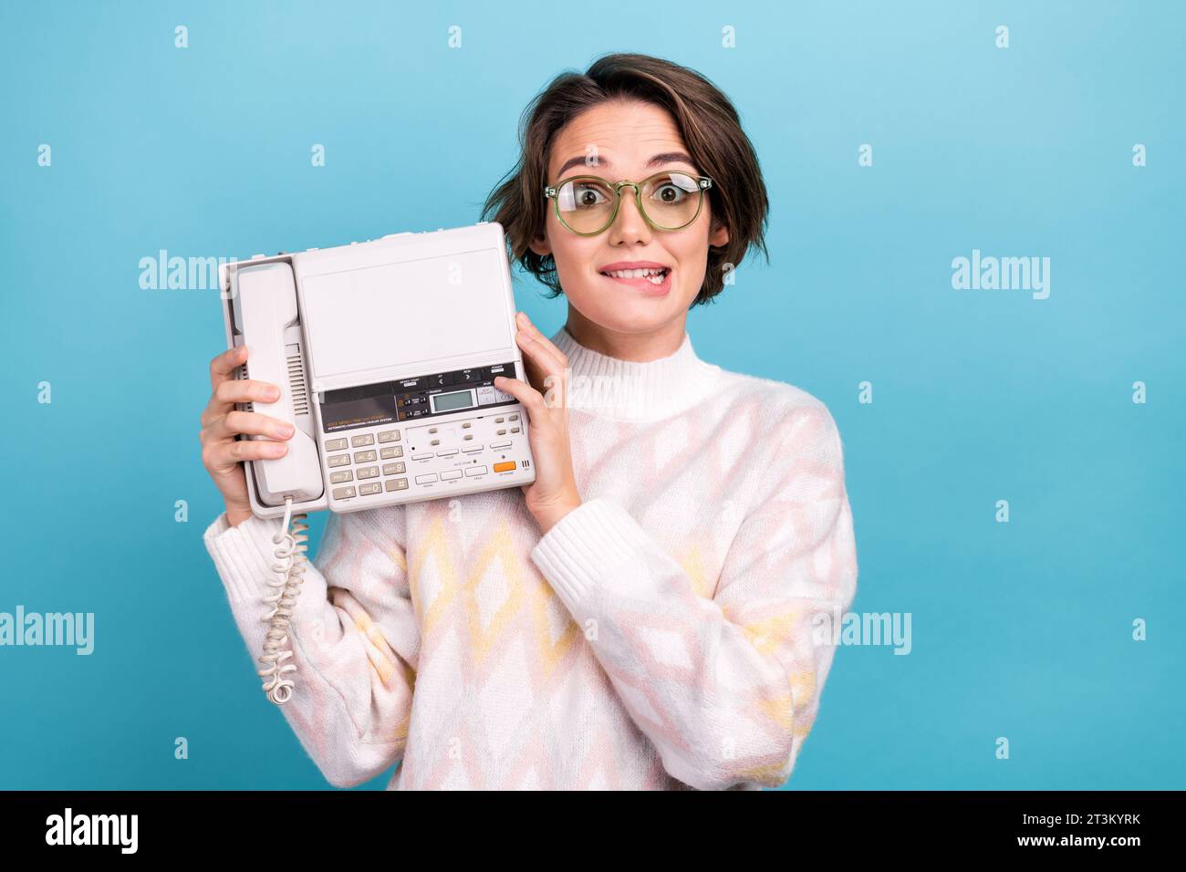 Portrait of cute intelligent girl biting lips hands hold showing old ...