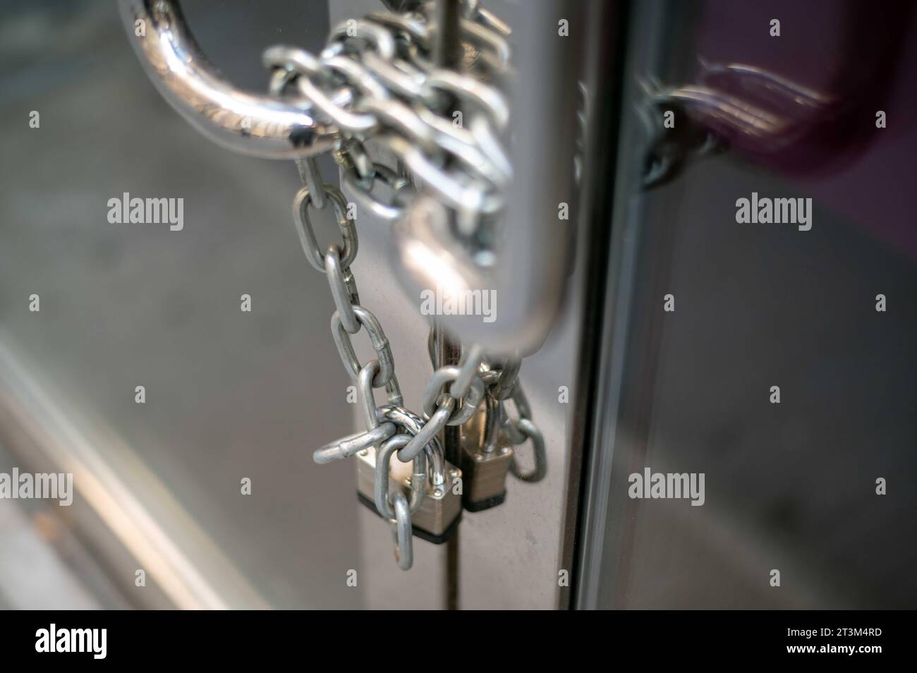 Chain and padlock on closed business glass door with metal handles ...