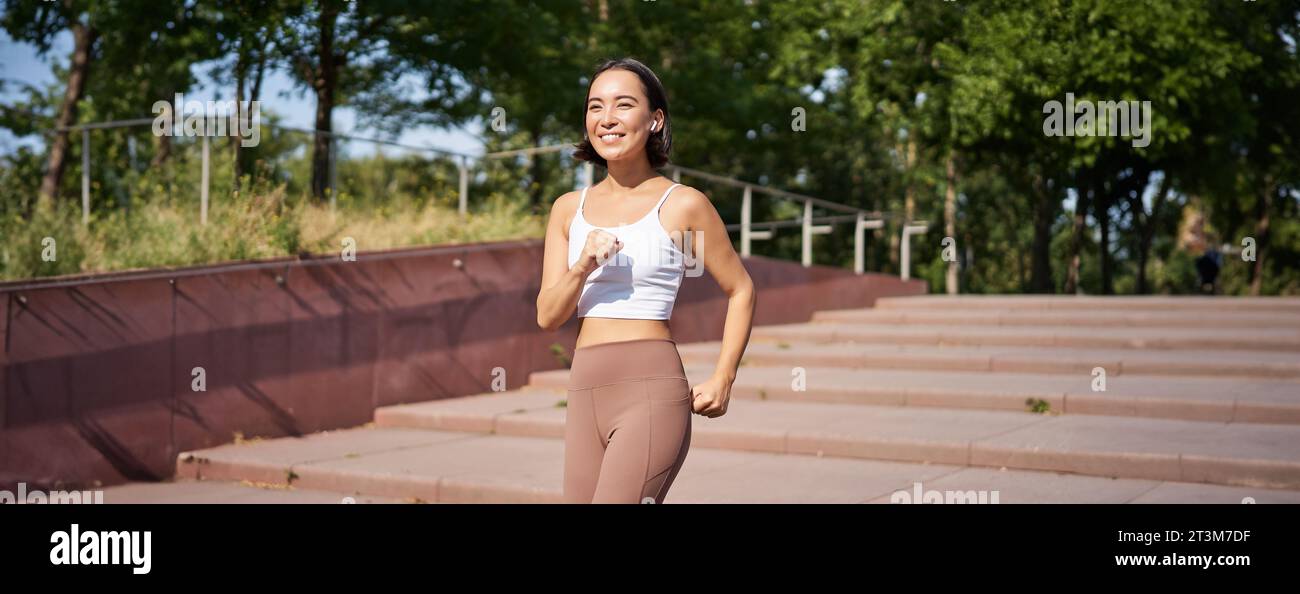 Wellbeing and sport. Asian fitness girl runner, jogging in park ...