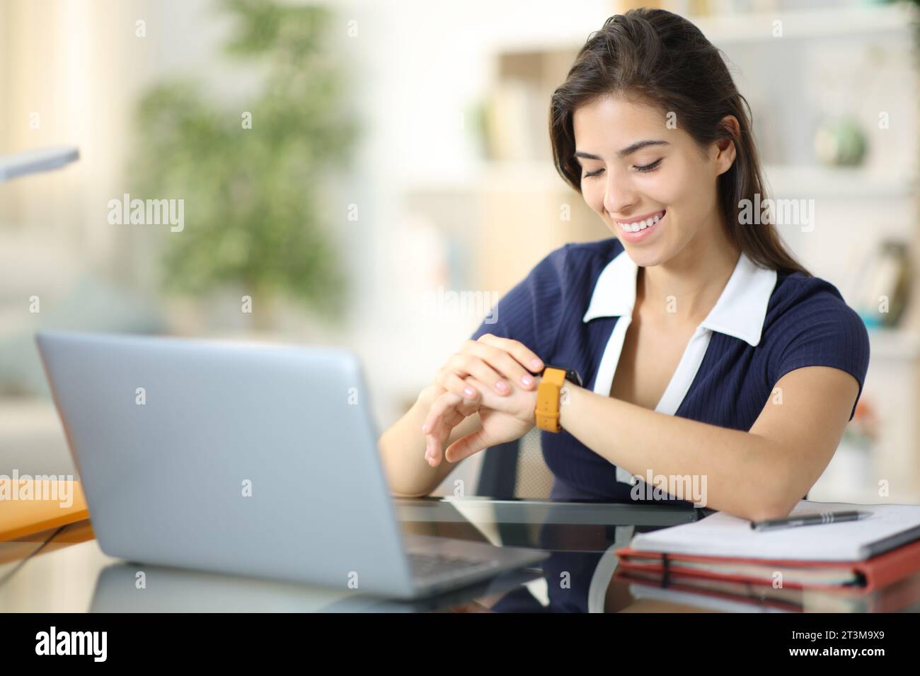 Happy student checking smartwatch sitting at home Stock Photo - Alamy