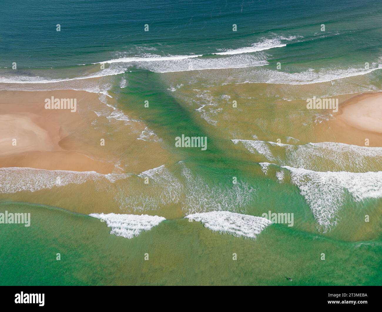 Aerial view of waves washing over a sand bar with a channel cutting ...