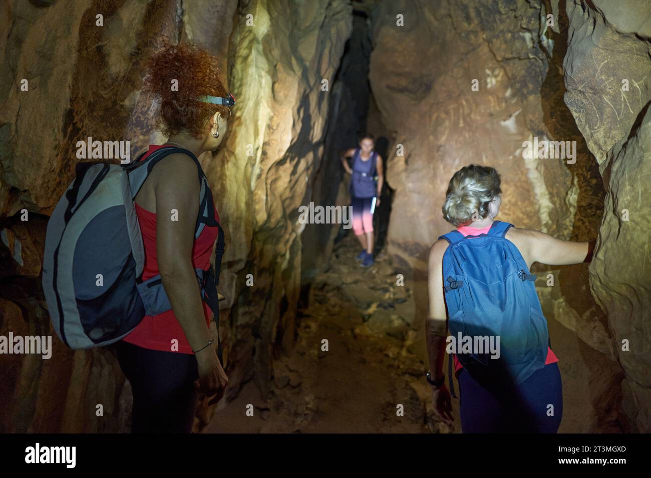 Three women with backpack exploring a cave with head torches Stock ...