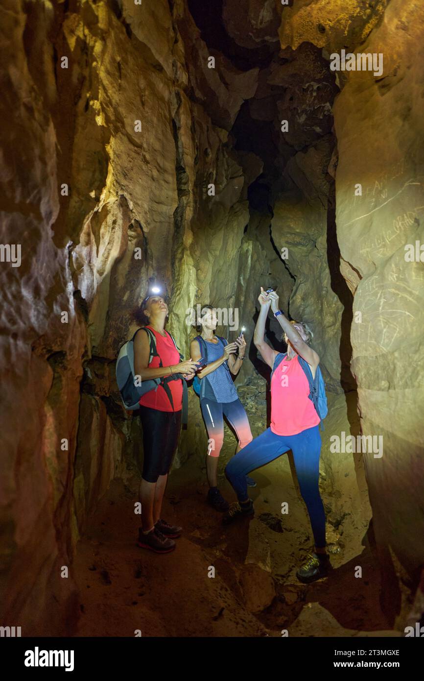 Three women with backpack exploring a cave with head torches Stock ...