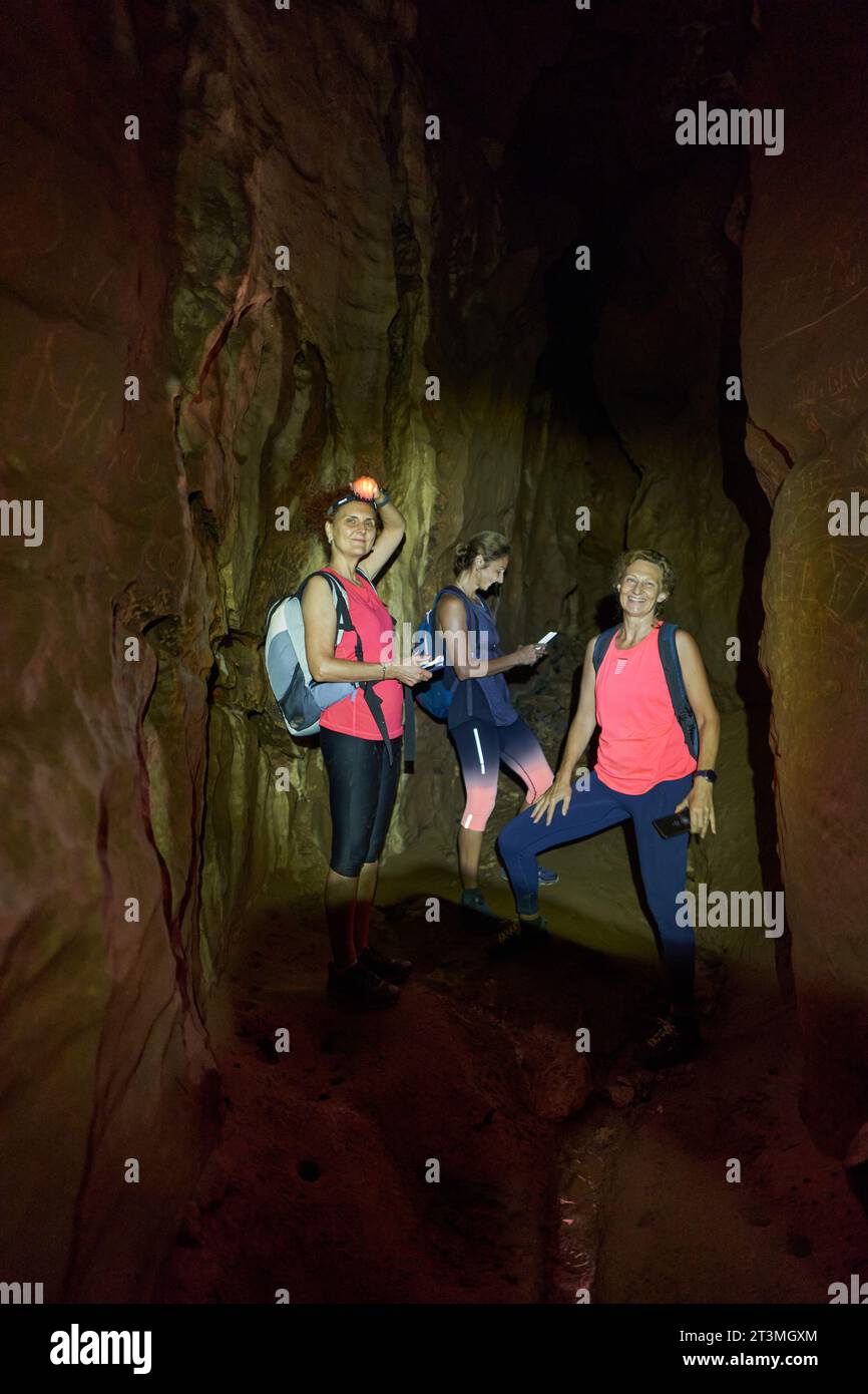 Three women with backpack exploring a cave with head torches Stock ...