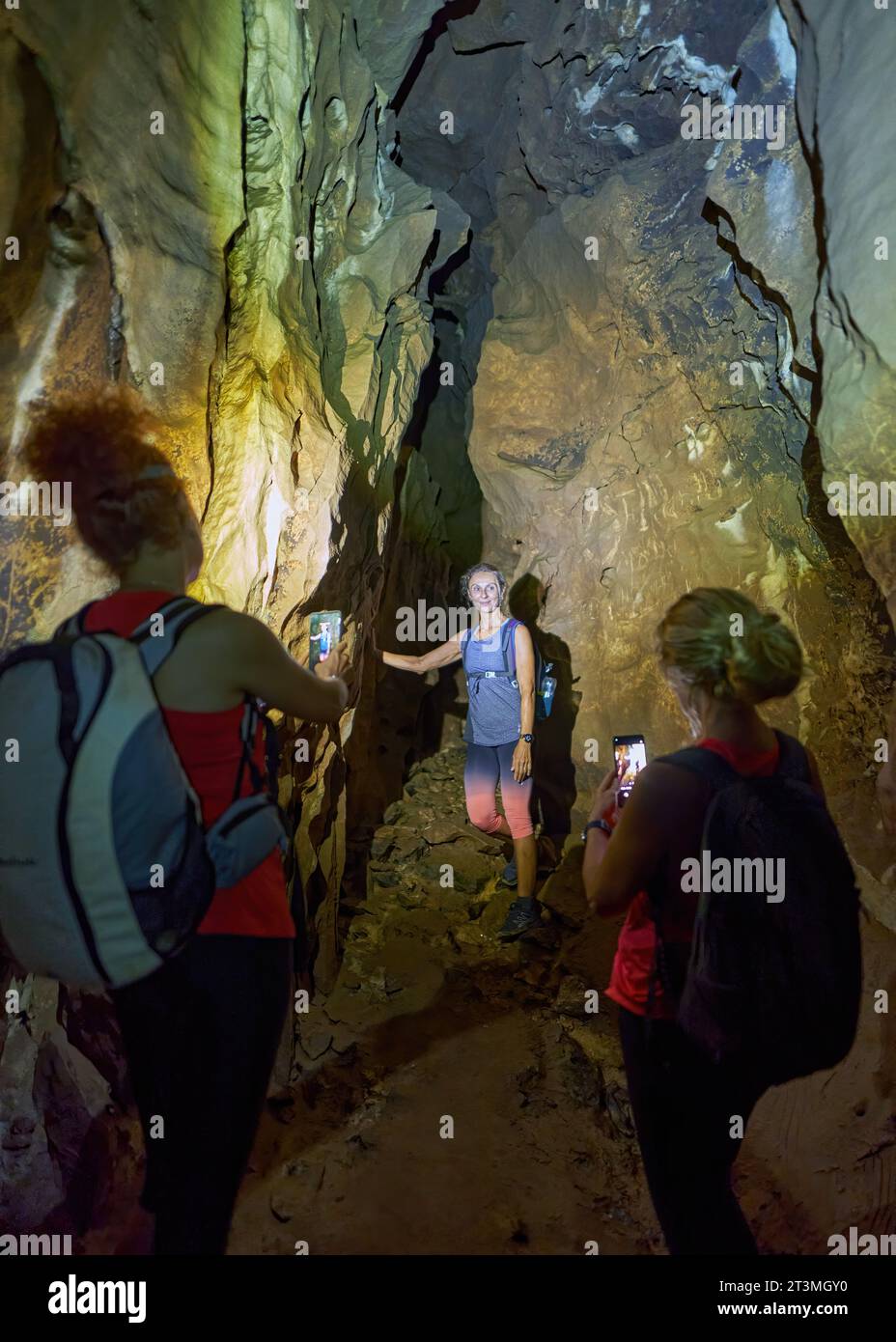 Three women with backpack exploring a cave with head torches Stock ...
