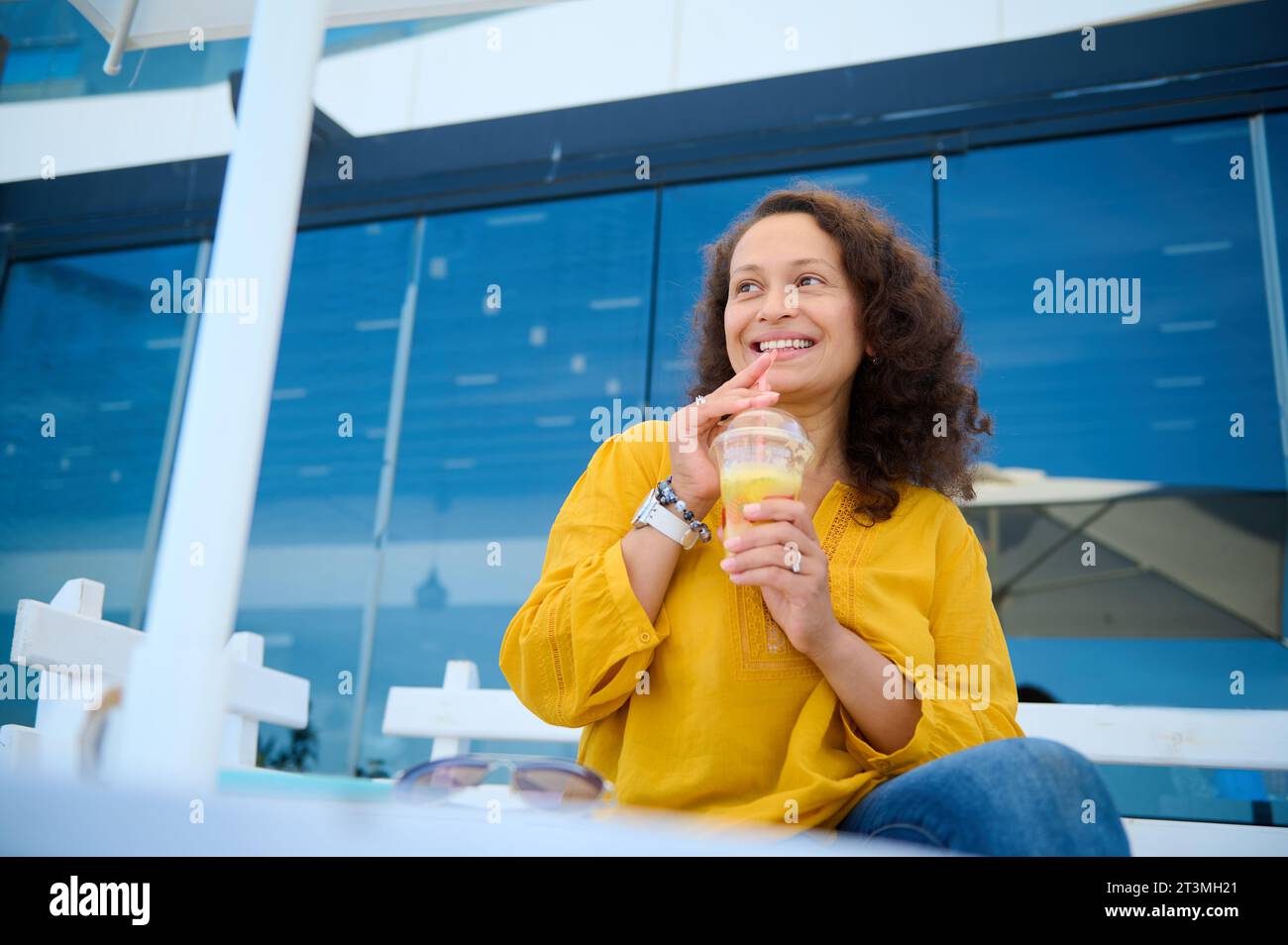 View from the bottom of happy multi-ethnic woman, taking a sip of ...