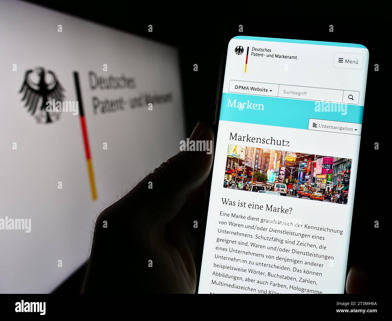 Person holding smartphone with webpage of German agency Deutsches ...