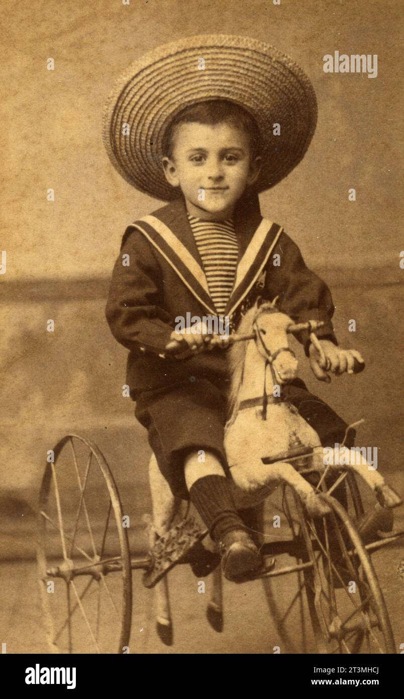 Studio portrait of a child dressed marina style with a tricycle, Italy ...