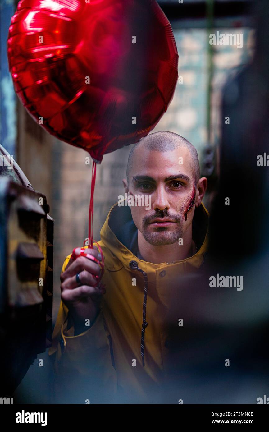 Man in Yellow jacket holding Red Balloon with cuts on face Stock Photo ...
