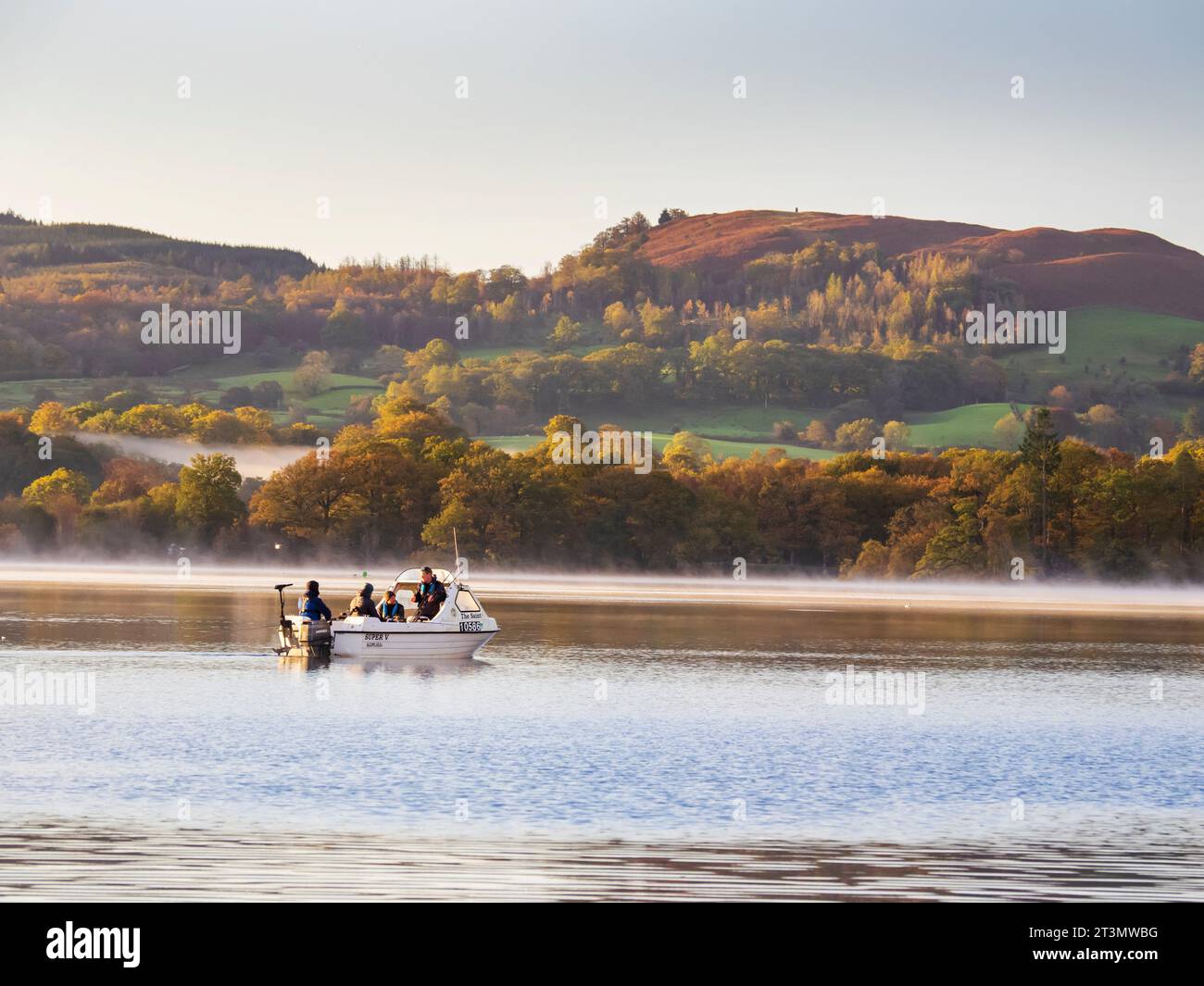 Mist drifting over Lake Windermere with people fishing in a boat in ...