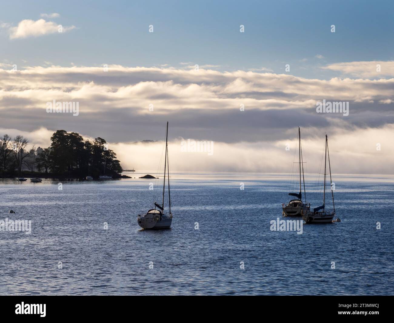 Mist drifting over Lake Windermere with sailing boats at sunrise in ...