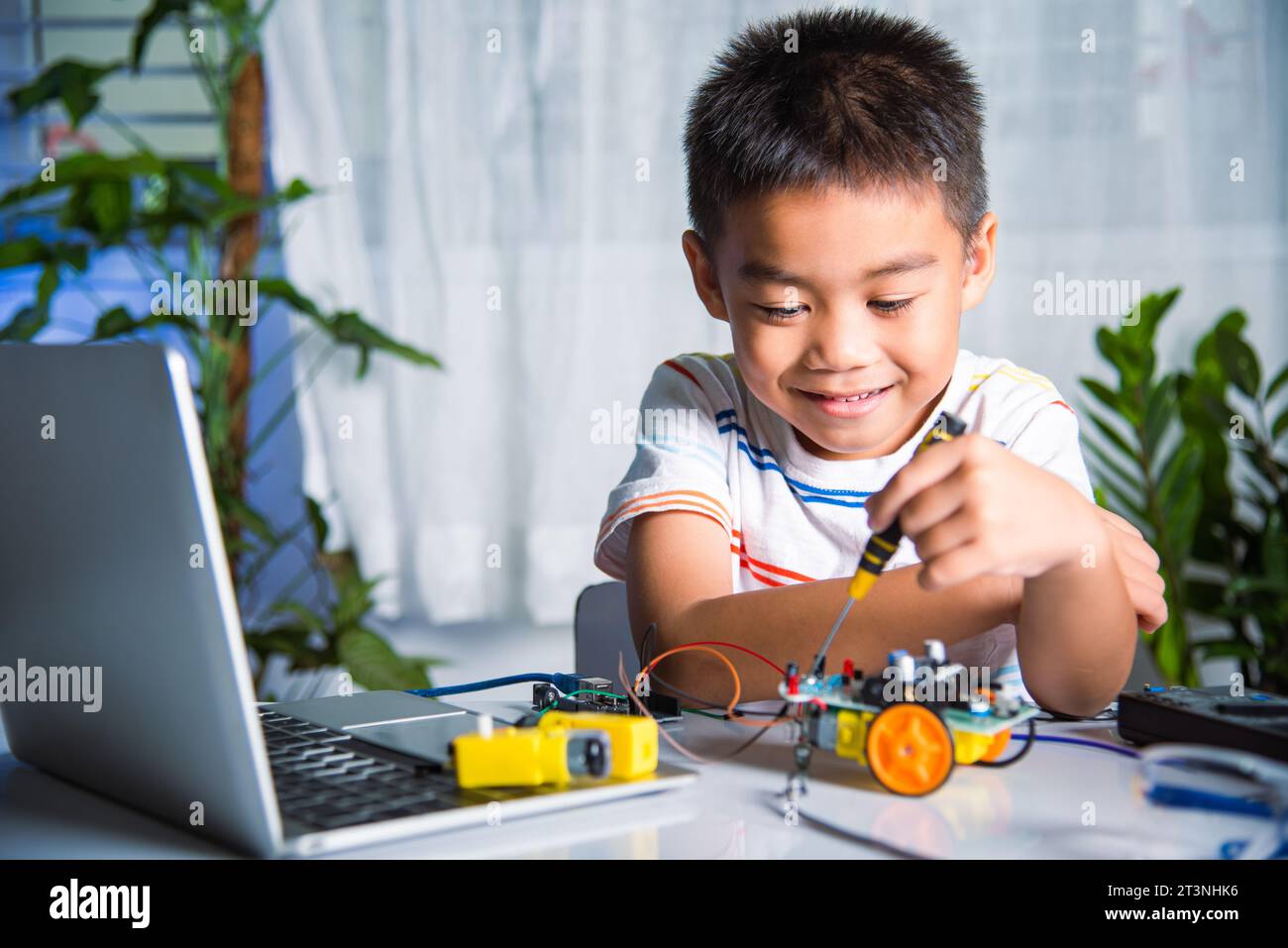 Asian kid boy assembling the Arduino robot car homework project at home ...