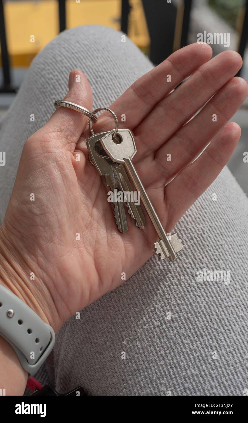 Young woman holding key of new house at home. Close-up view of keys ...