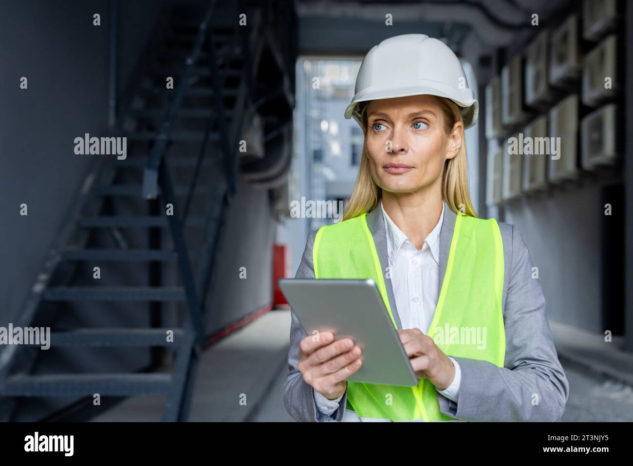 Serious confident thinking female engineer with tablet computer ...