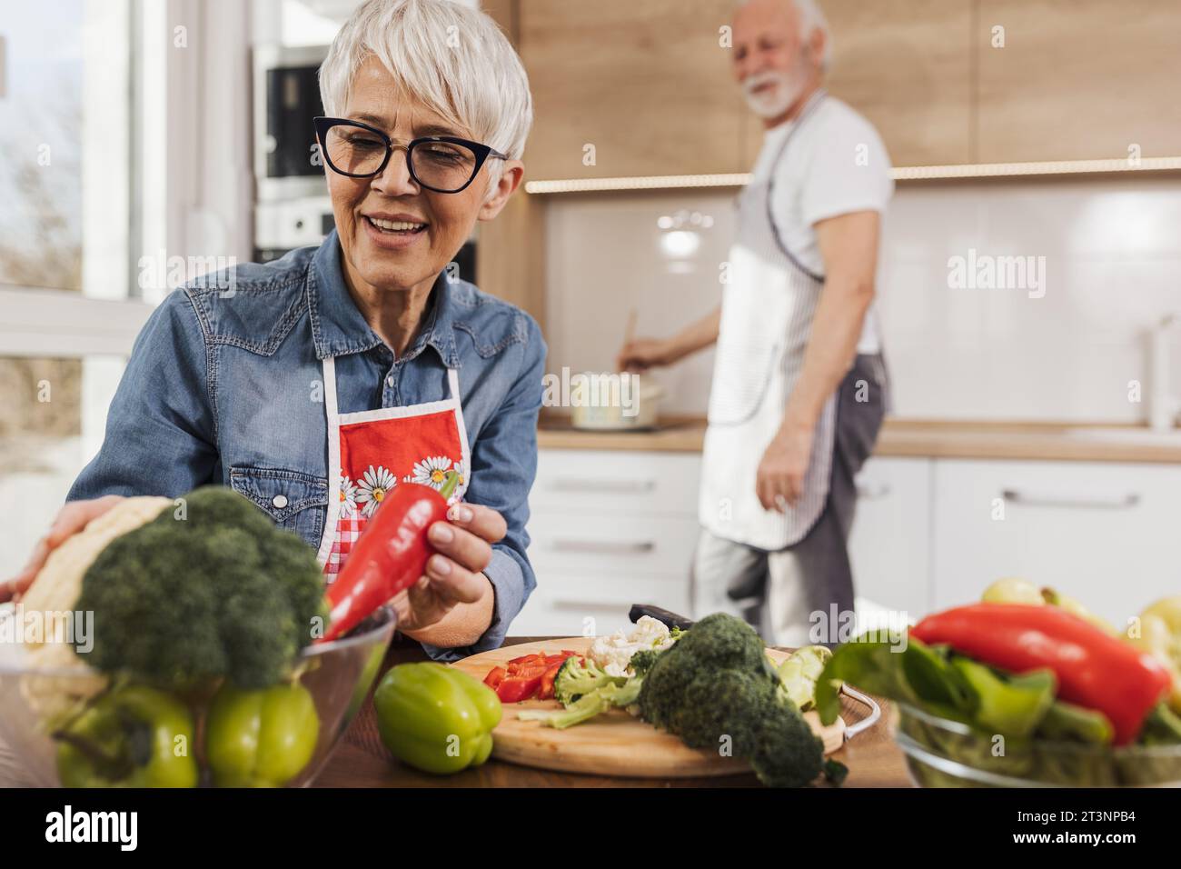 Senior couple preparing soup, wife cutting vegetable while husband ...