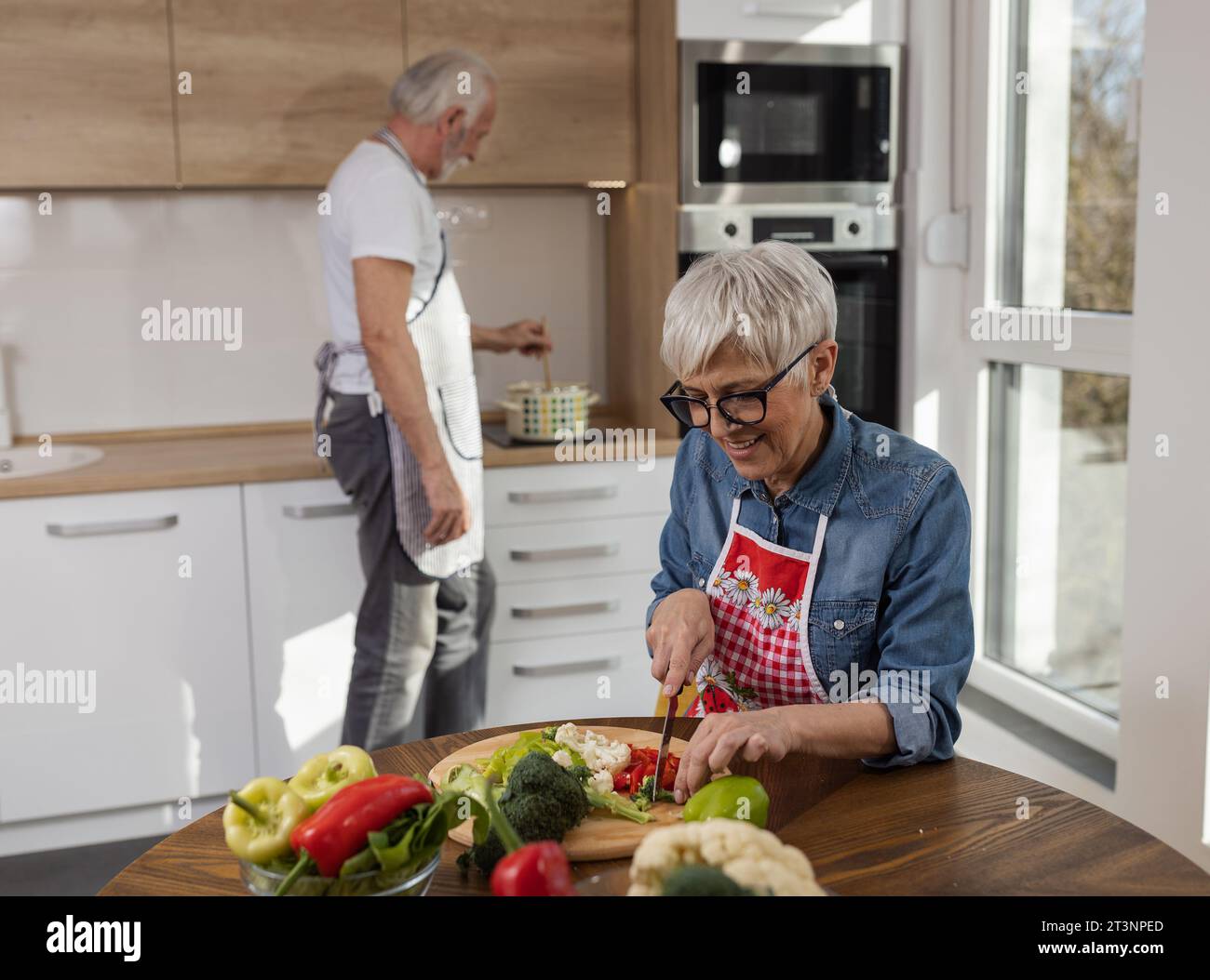 Senior couple preparing soup, wife cutting vegetable while husband ...