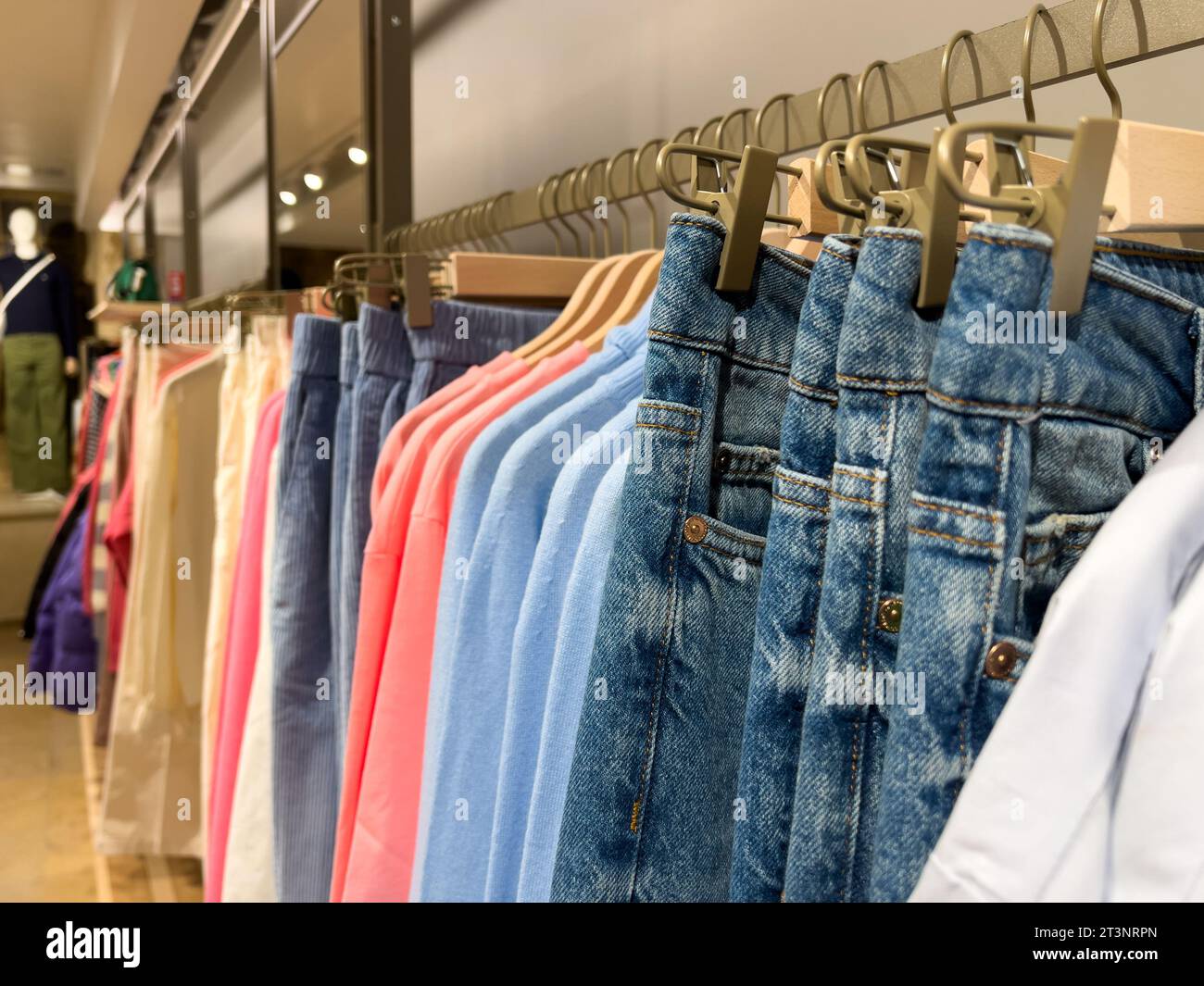 Inside a clothing store, various clothes hang on racks, with a focus on ...