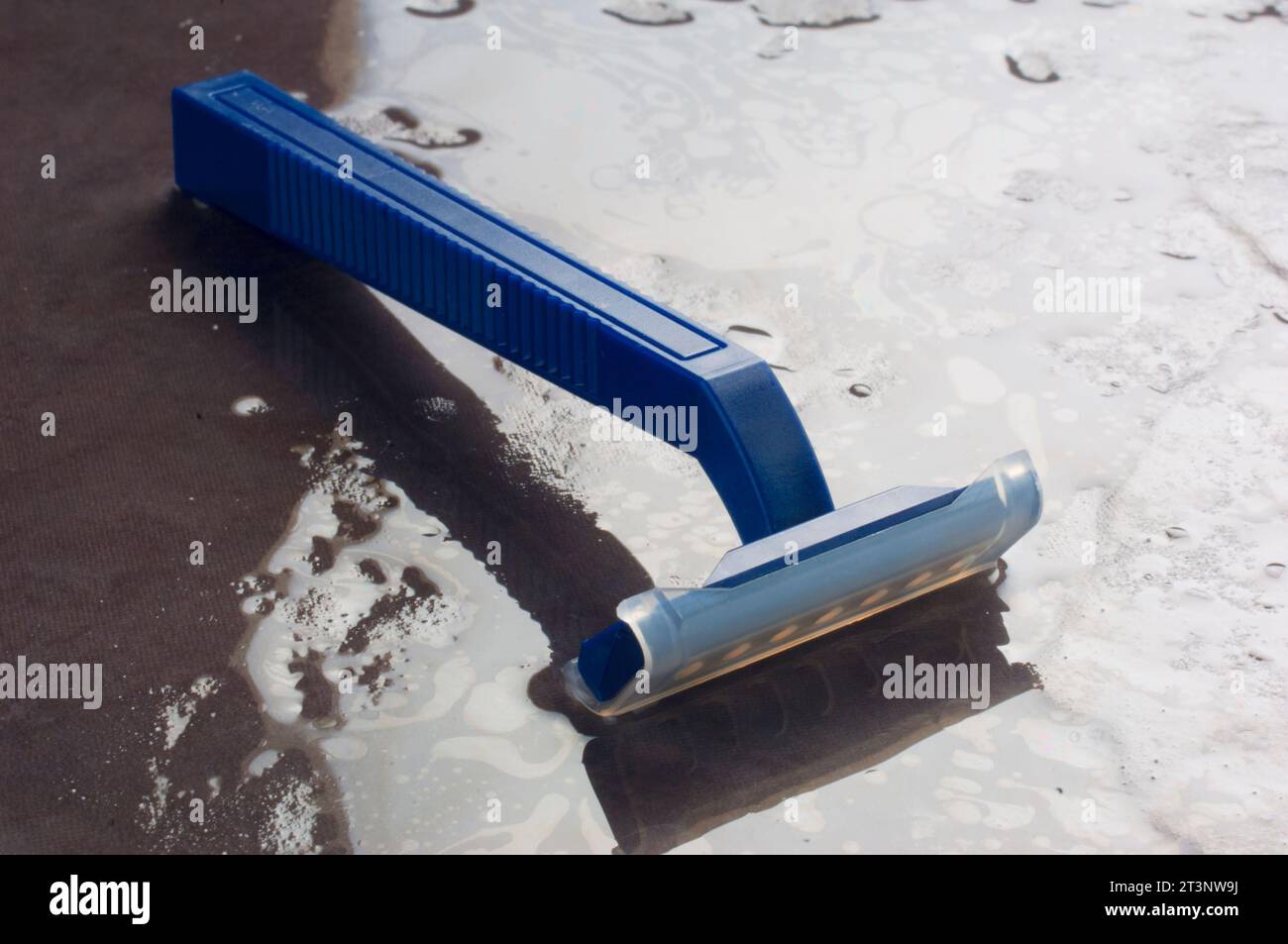 Studio shot of a plastic disposable razor on a wet slate background ...