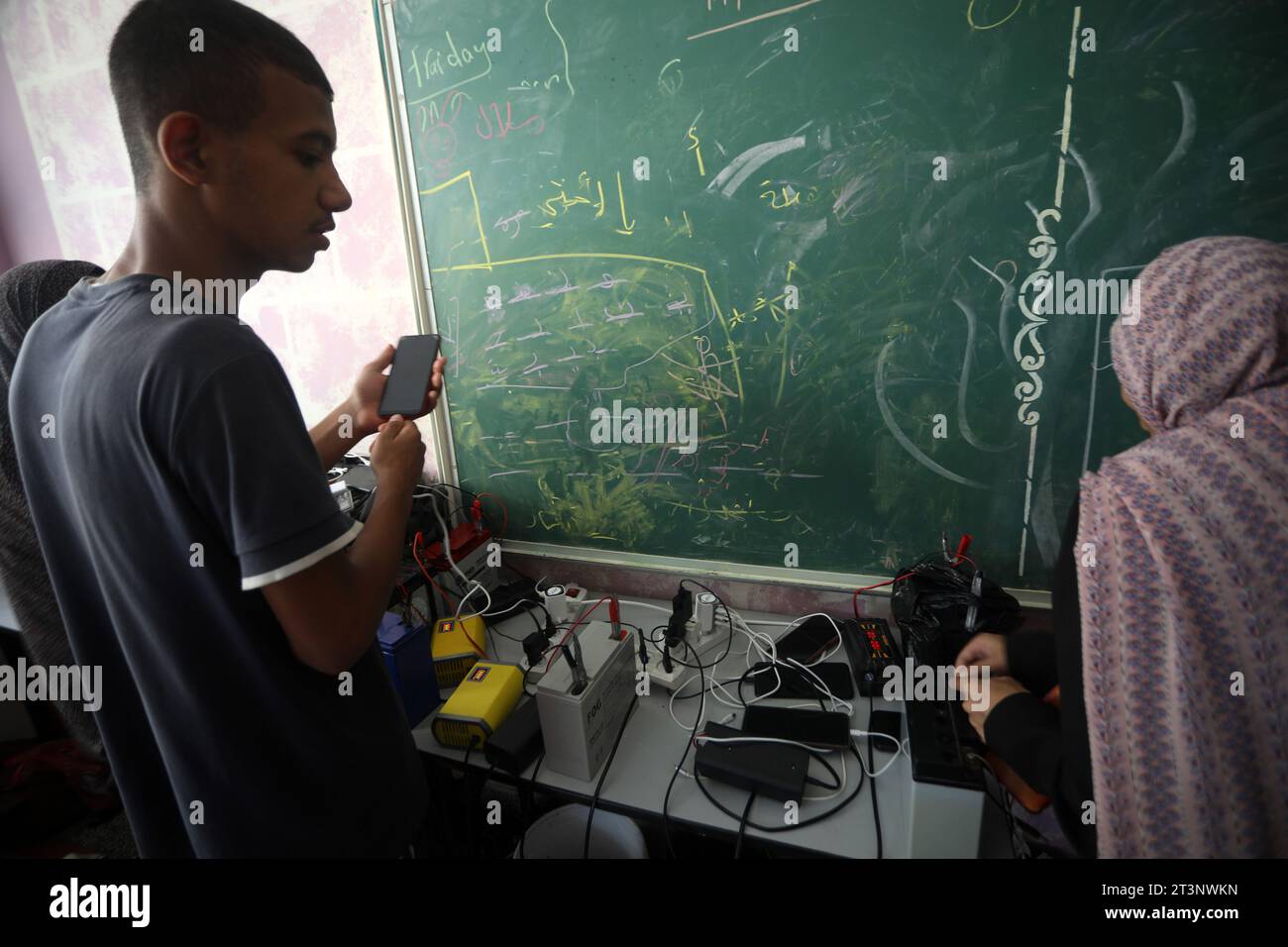 Palestinian refuge charge their mobile phones at a collective ...