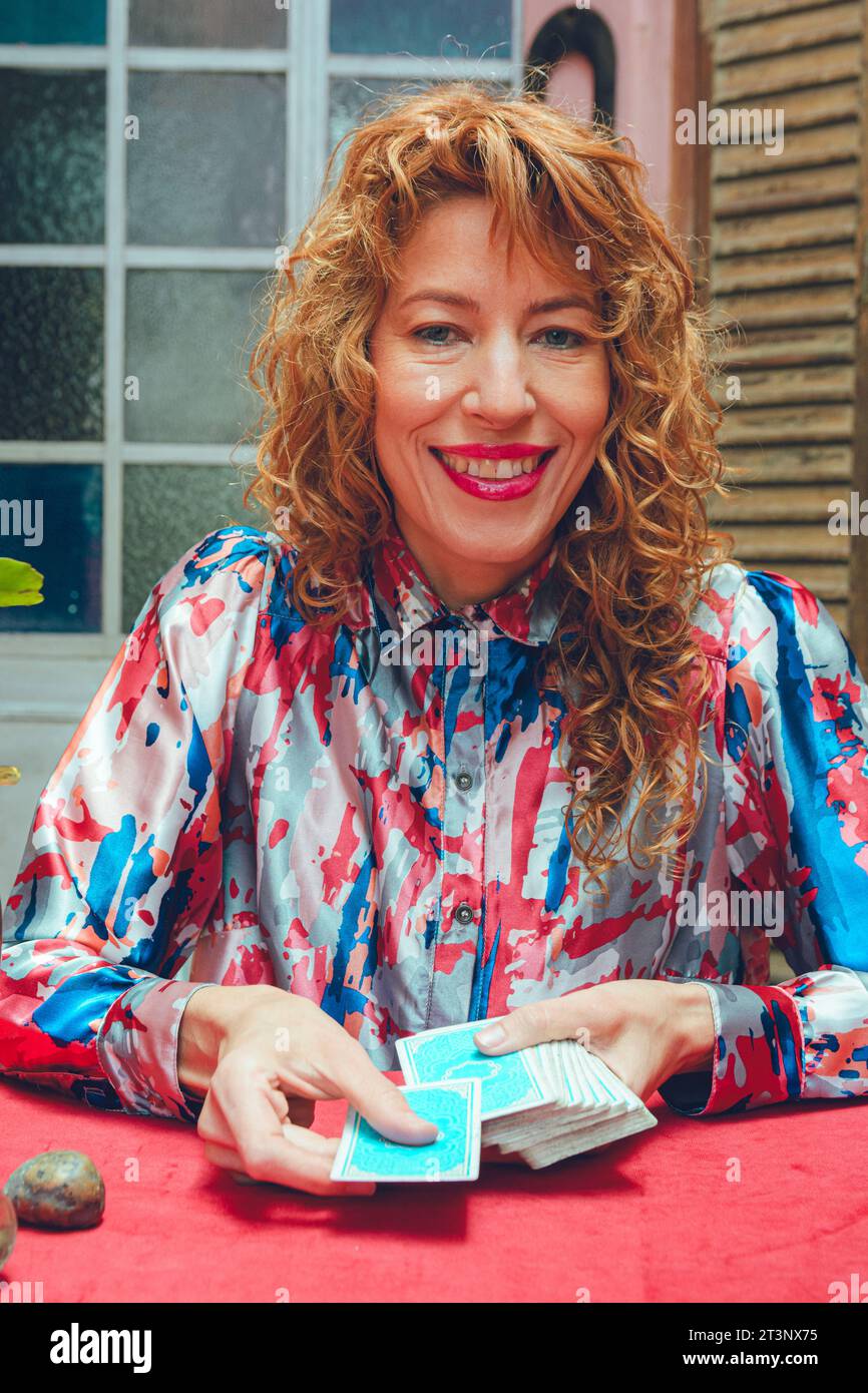 vertical image of curly latin woman tarot reader sitting laughing ...