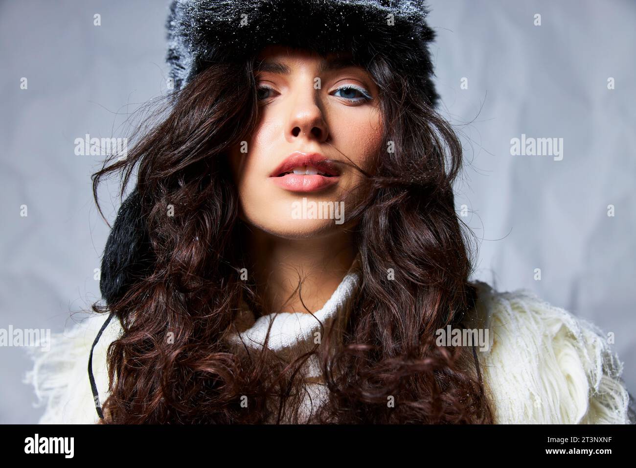 snow queen, curly brunette woman in furry snowy hat and sweater looking ...