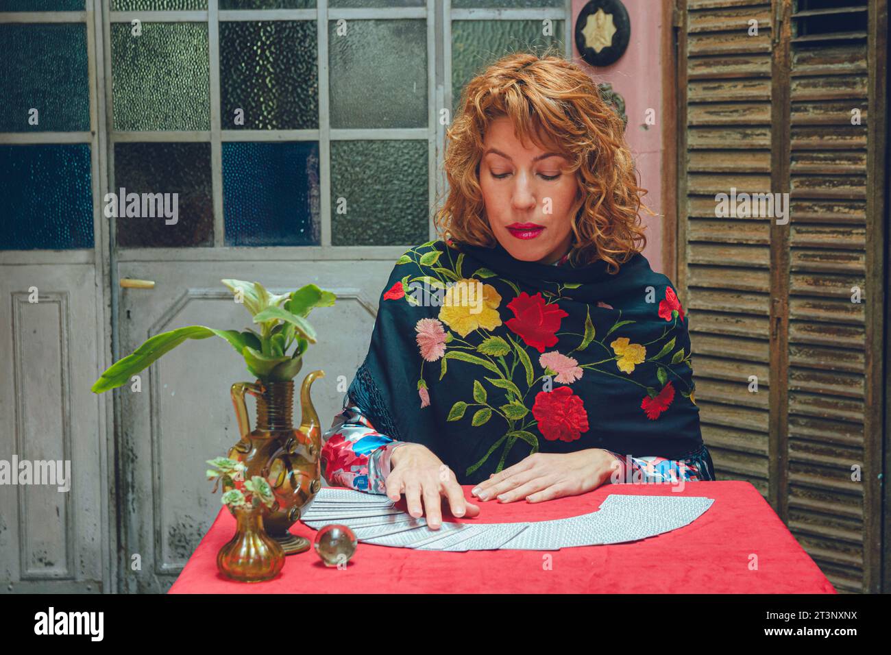 Front view of elegant blonde-haired Latin tarot reader woman sitting at ...