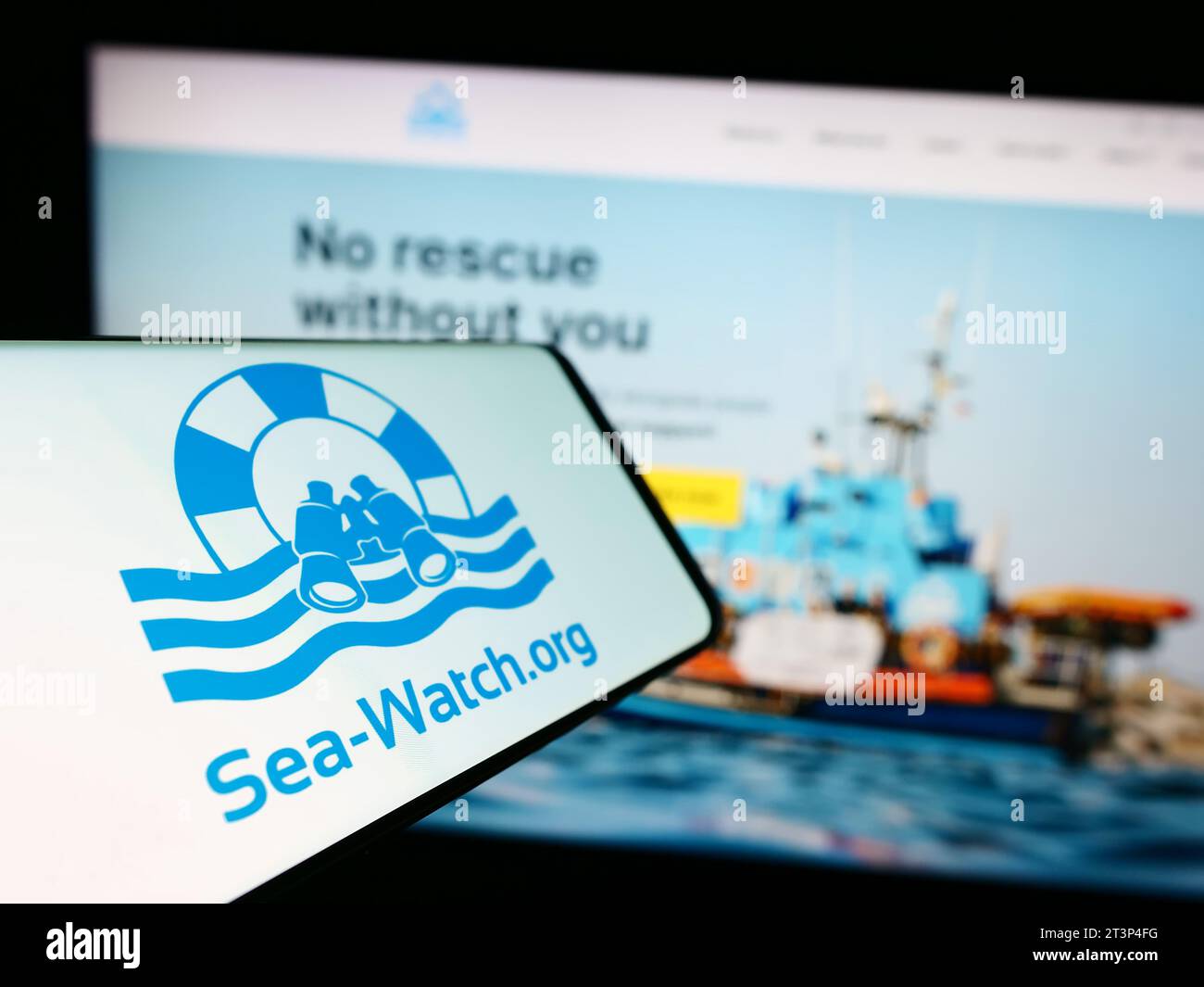 Mobile phone with logo of German association Sea-Watch e.V. in front of website. Focus on center ...