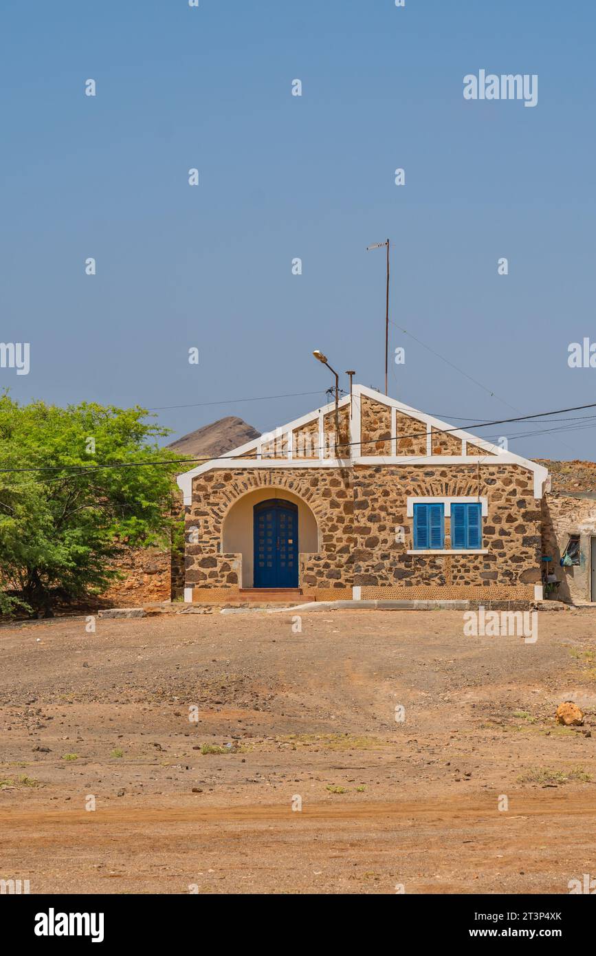 Stone building with blue window and door and a green tree on Sal island ...