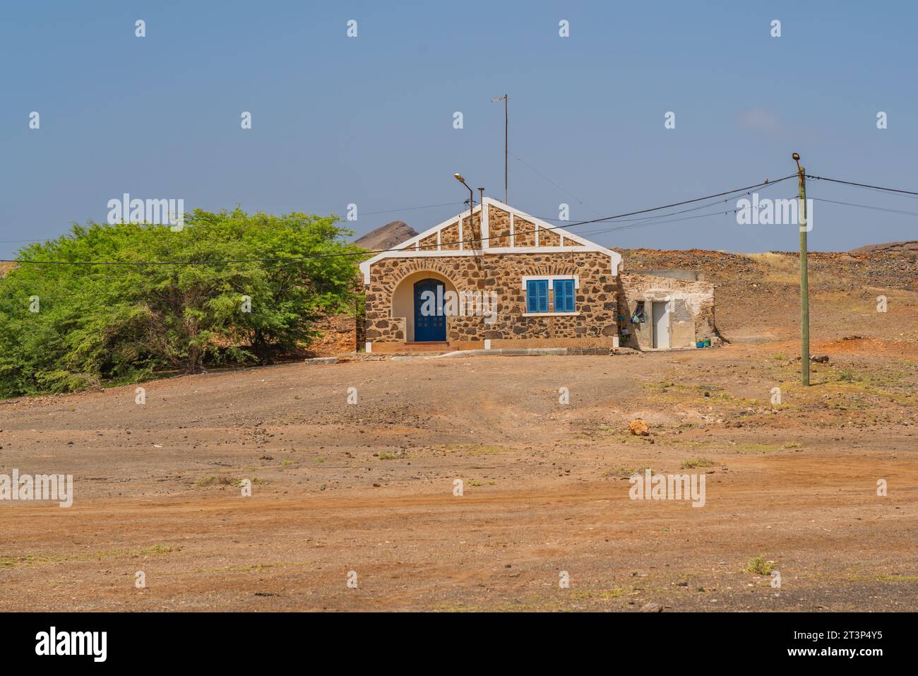 Stone building with blue window and door and a green tree on Sal island ...