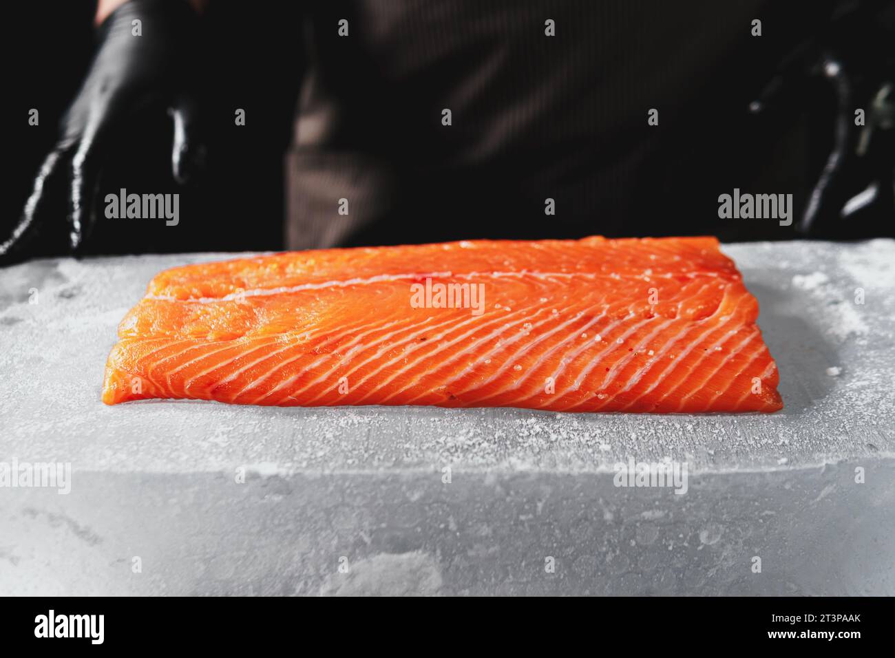 Close-up of chef hand prepared to cooking fresh salmon fillet, black ...