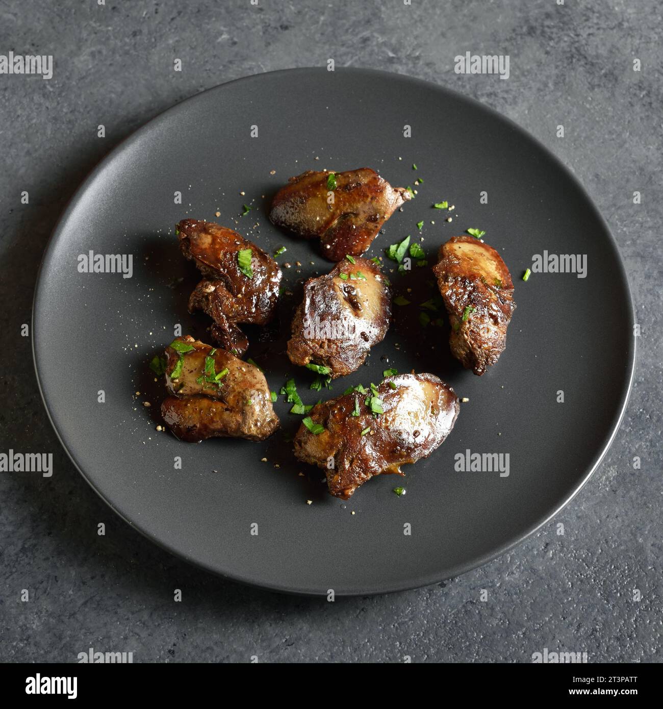 Close up view of roasted chicken liver on plate over dark stone ...