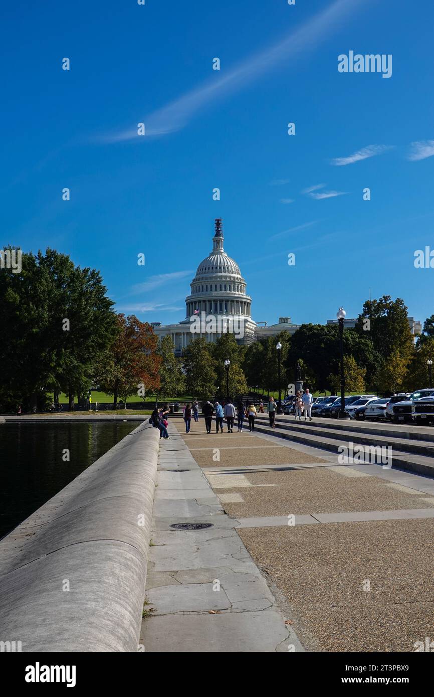 Capitol dome in background with people passing by the reflecting pool ...