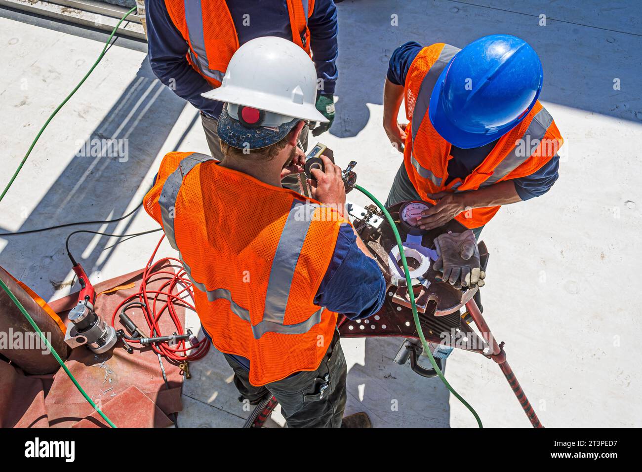 Three construction workers gathered around a workbench on the roof of a ...