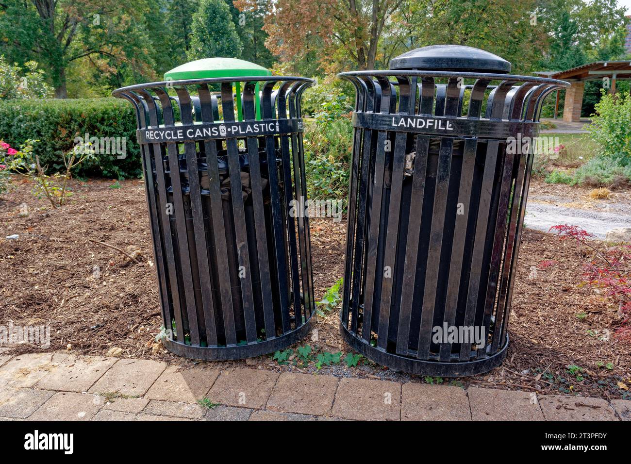 Two garbage cans along the walkway in the park one for cans and plastic ...