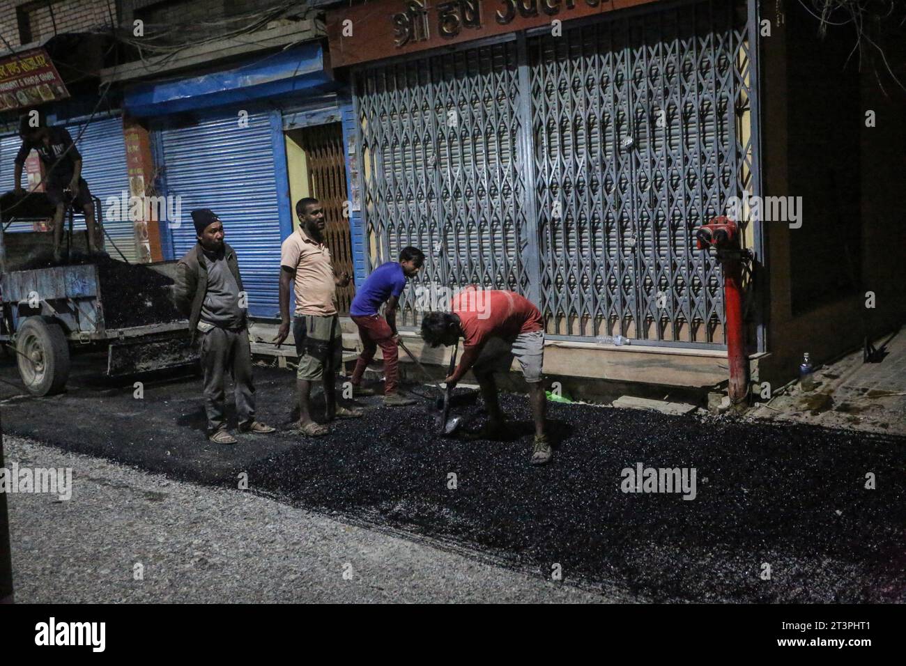 Kathmandu, Bagmati, Nepal. 26th Oct, 2023. Indian migrant workers spread asphalt while ...