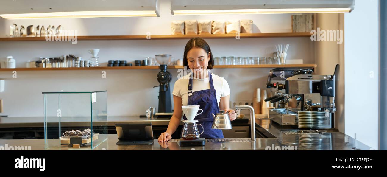 Smiling asian girl barista, working in cafe, brewing coffee v60 ...