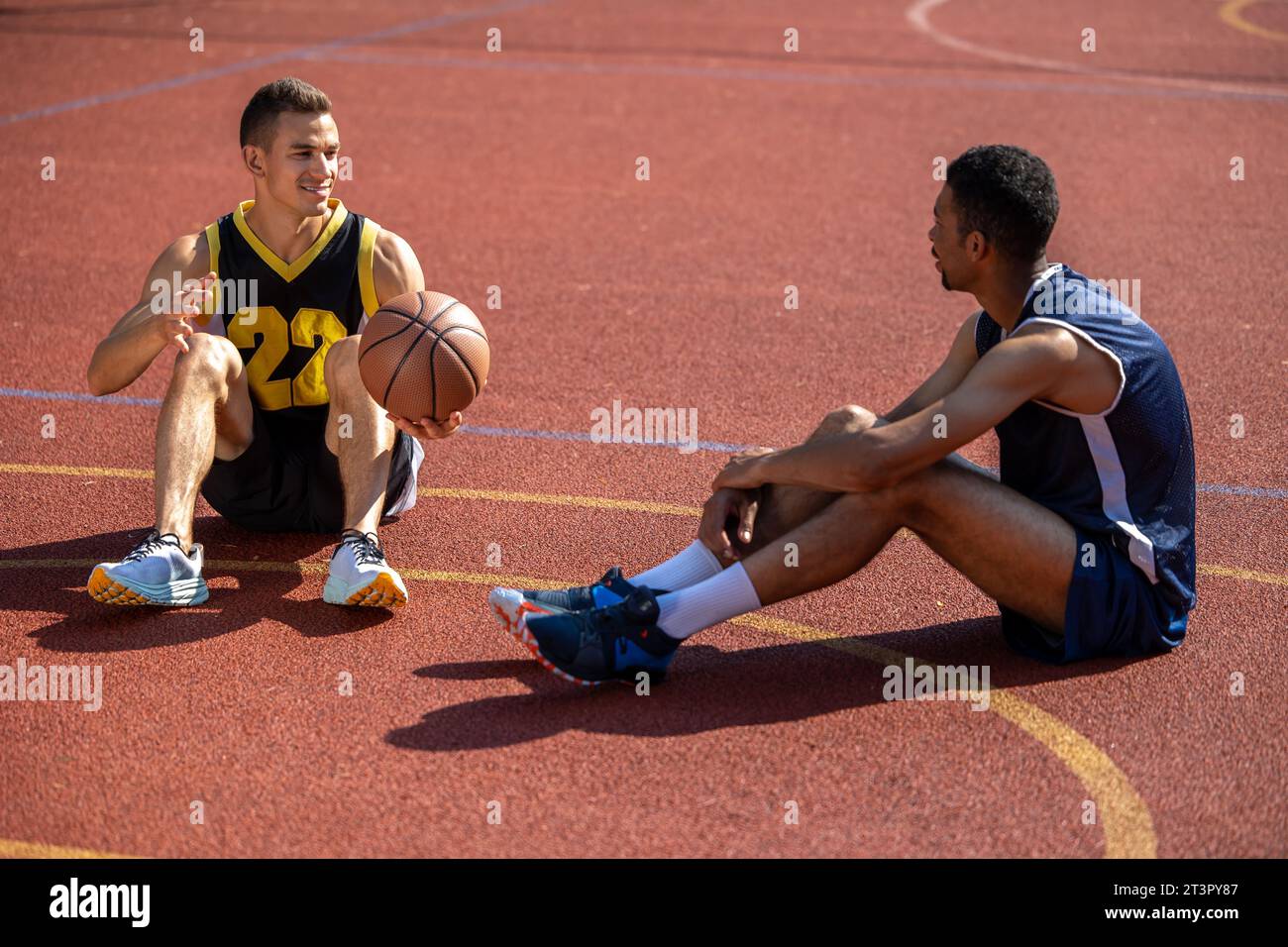 Men friends basketball players sitting together on court Stock Photo ...