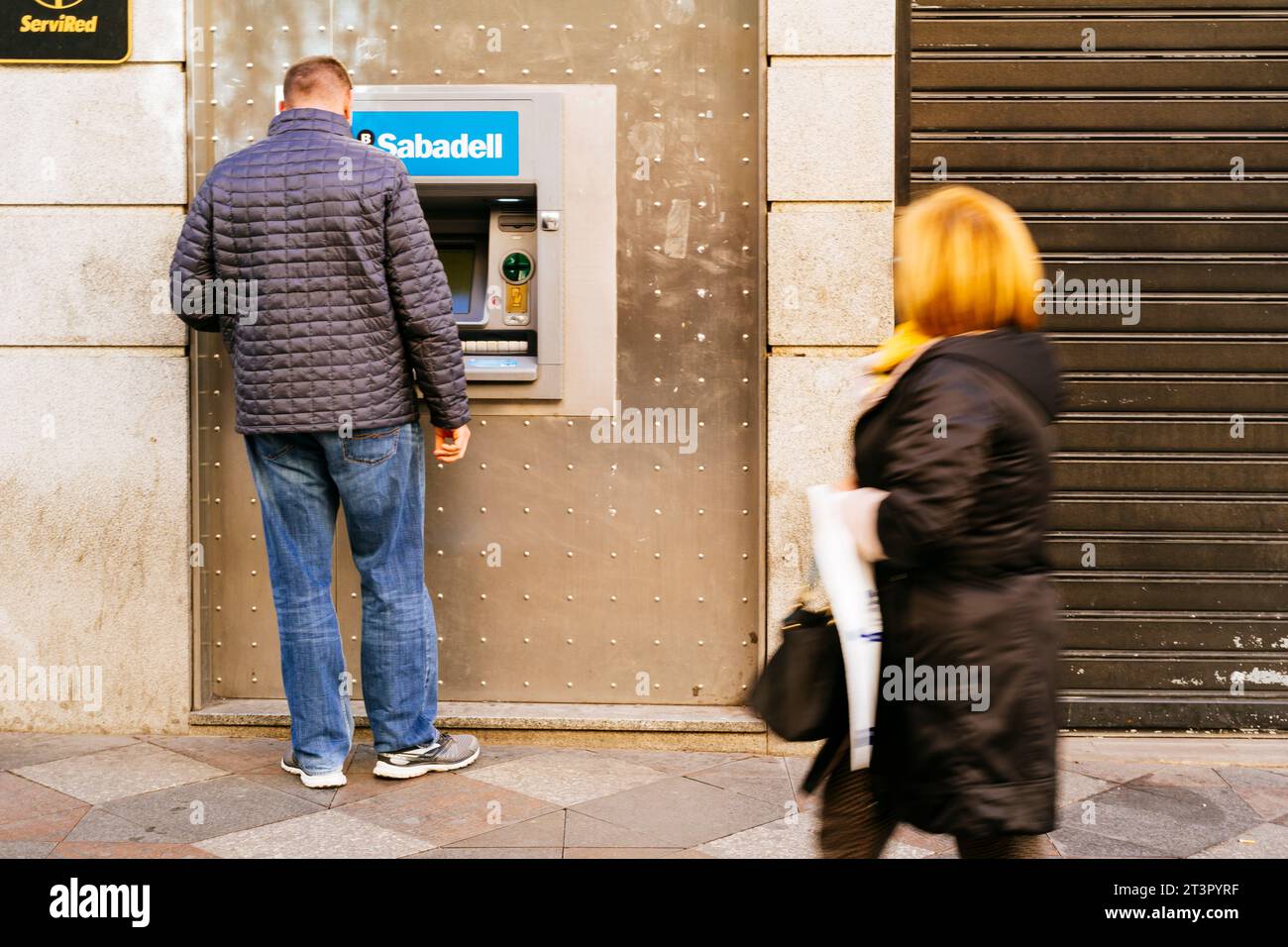 Street scene, man next to ATM of the bank of Sabadell. Madrid ...