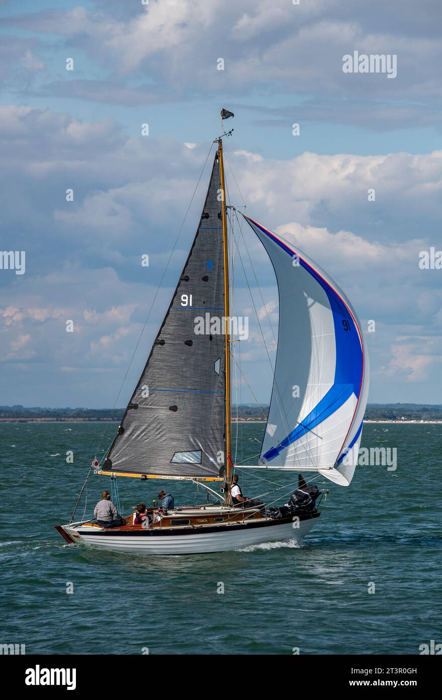 sailing yacht under full sail with spinnaker under a cloudy sky on a ...