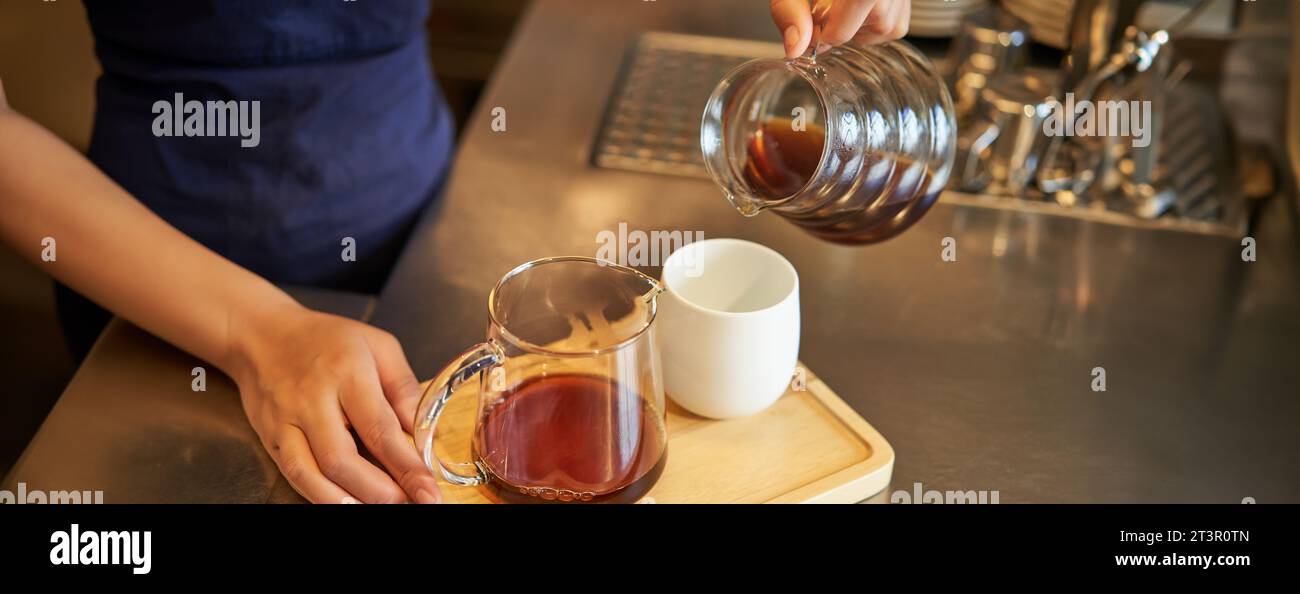 Close up of female barista hands pouring filter coffee into cup ...