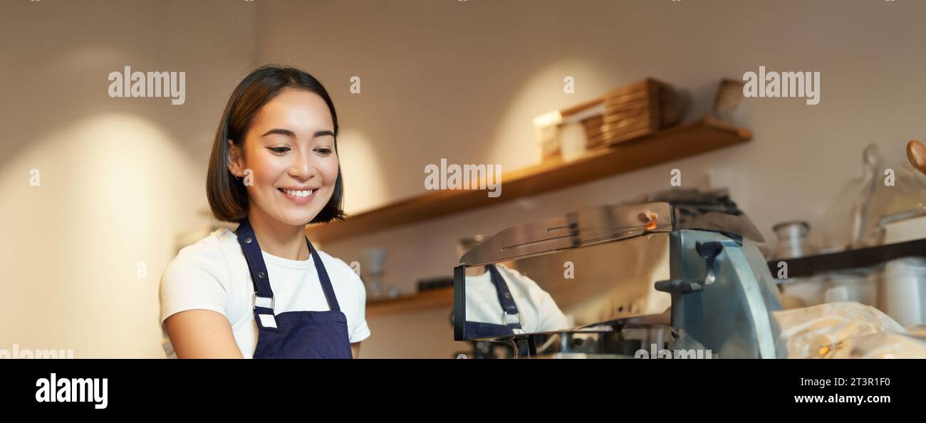 Portrait of cute barista girl working behind counter, making coffee ...