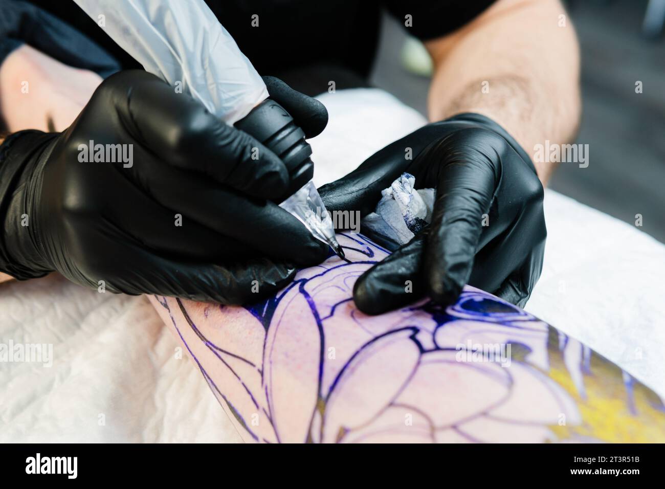 Professional tattoo artist makes a tattoo on the male leg, close-up ...