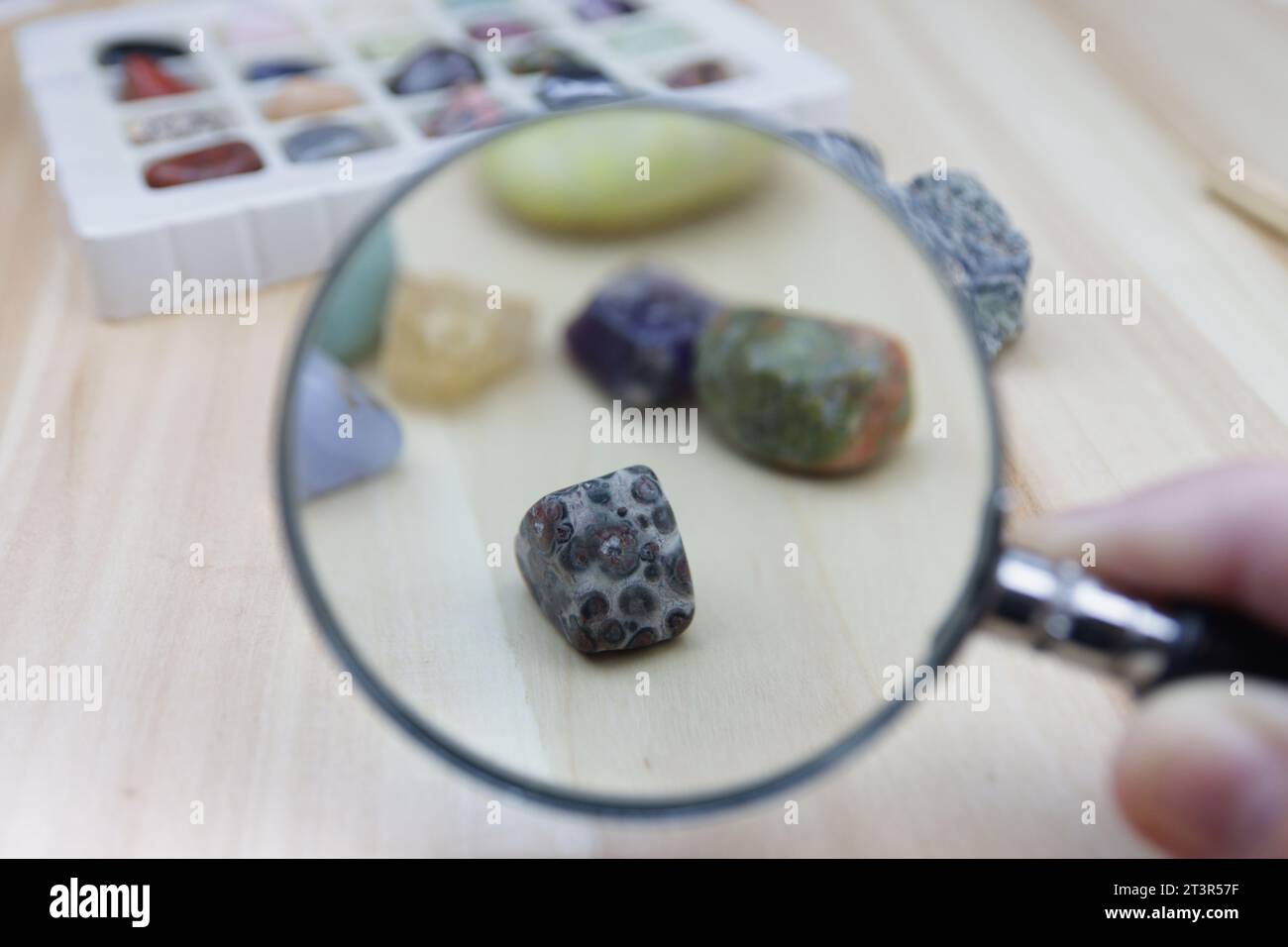 A few semi-precious stone minerals through a magnifying glass held by a ...