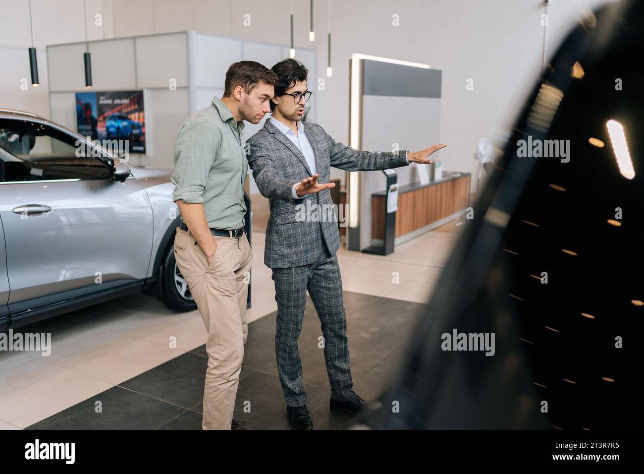 Side view of car salesman in business suit telling handsome interested ...