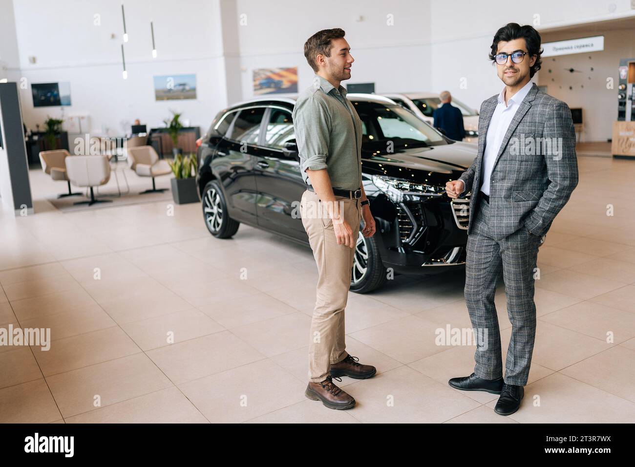 Full length portrait of professional male car seller with bearded male ...