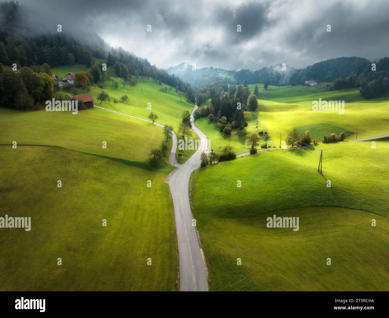Aerial view of country road in green alpine meadows in fog Stock Photo ...